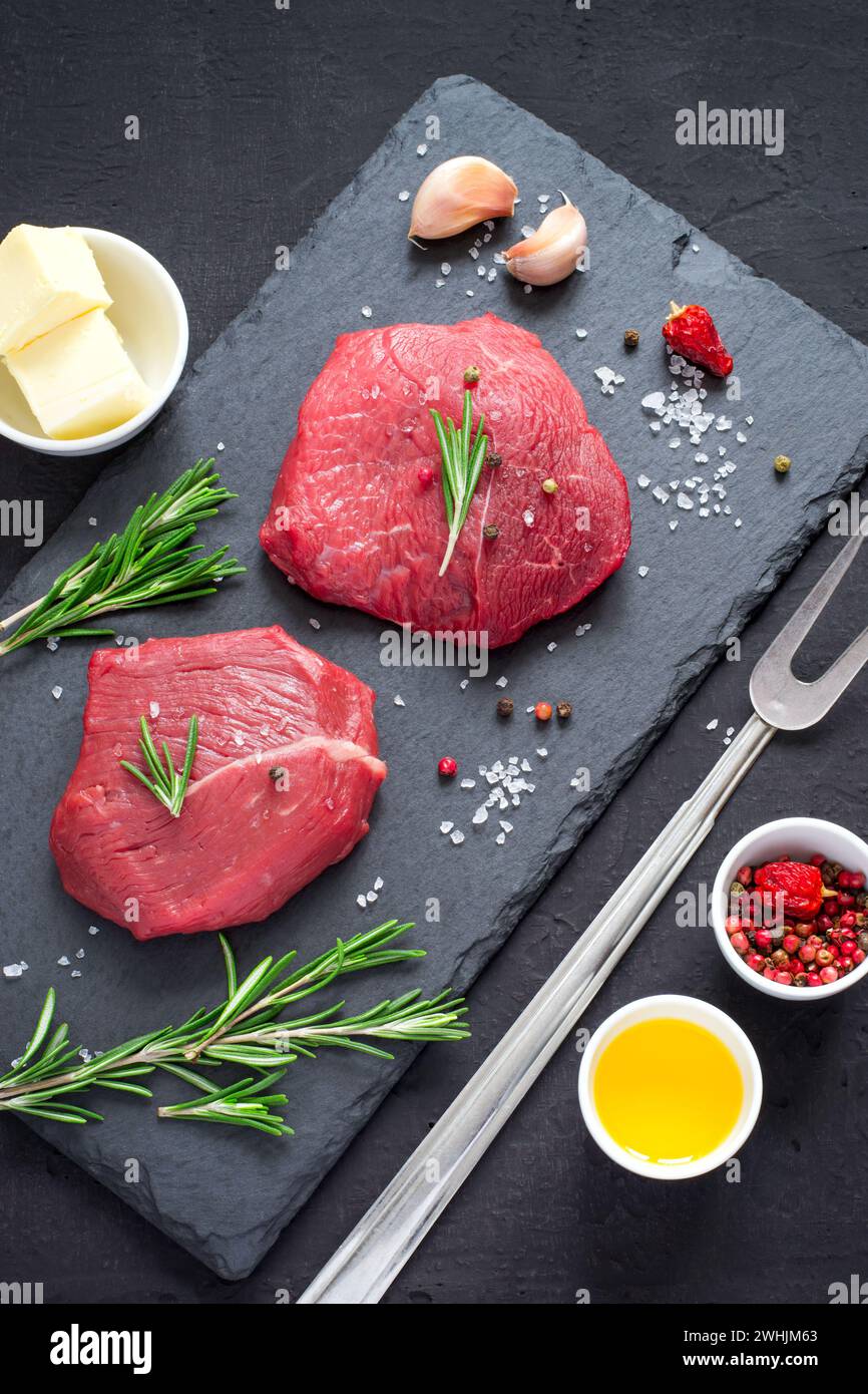 Raw meat beef steaks on black slate board, spices and ingredient Stock ...