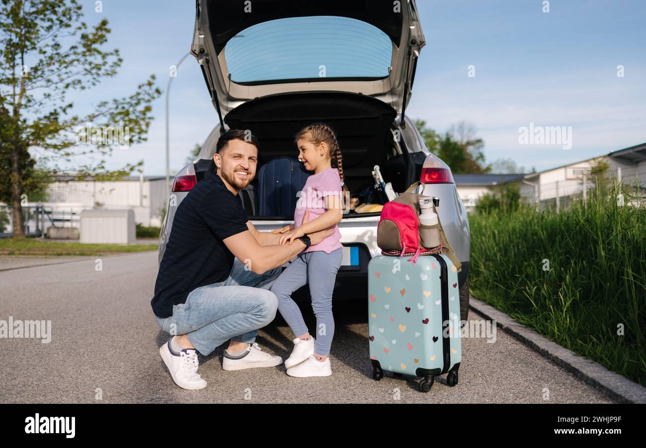 Father help daughter loading to the trunk with luggage before traveling while mom packs her ...