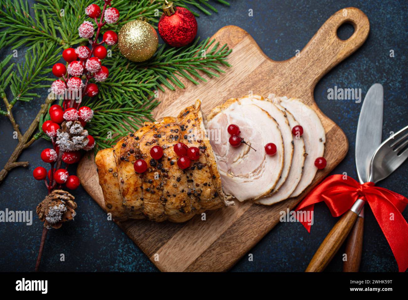 Christmas baked ham sliced with red berries and festive decorations ...