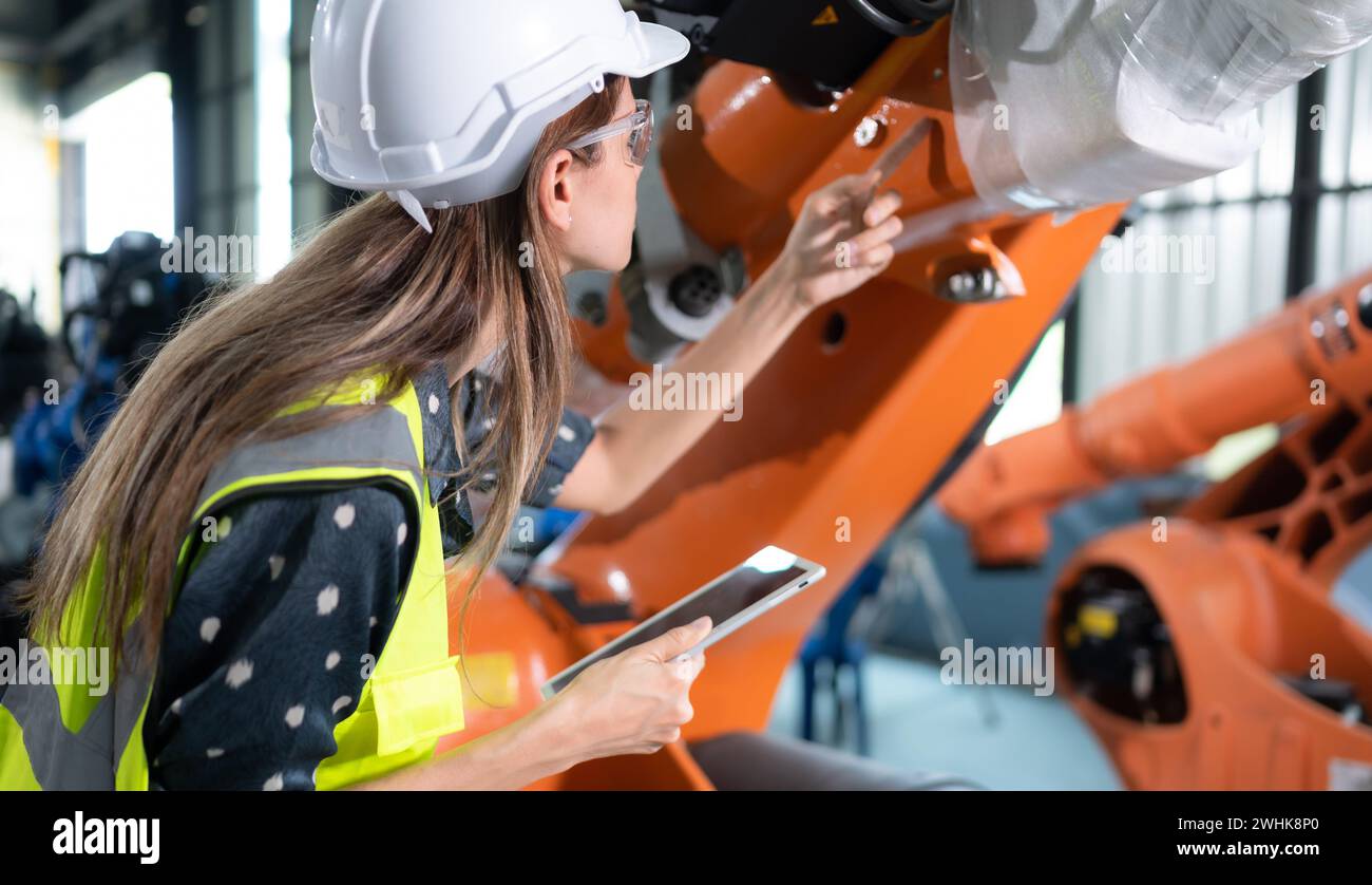 A female engineer installs a program on a robotics arm in a robot ...