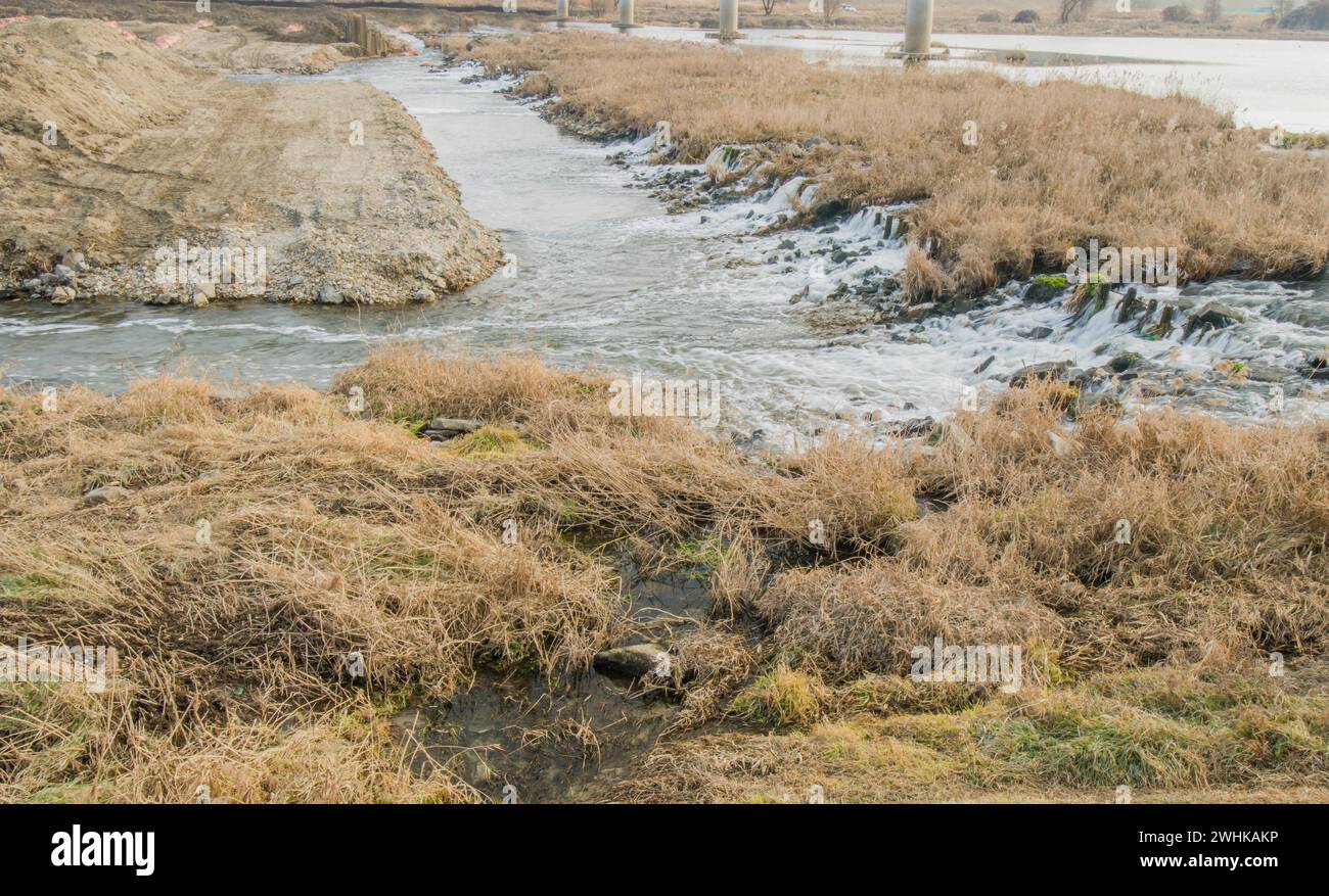 Water running swiftly over rocks into a man made canal with signs of ...