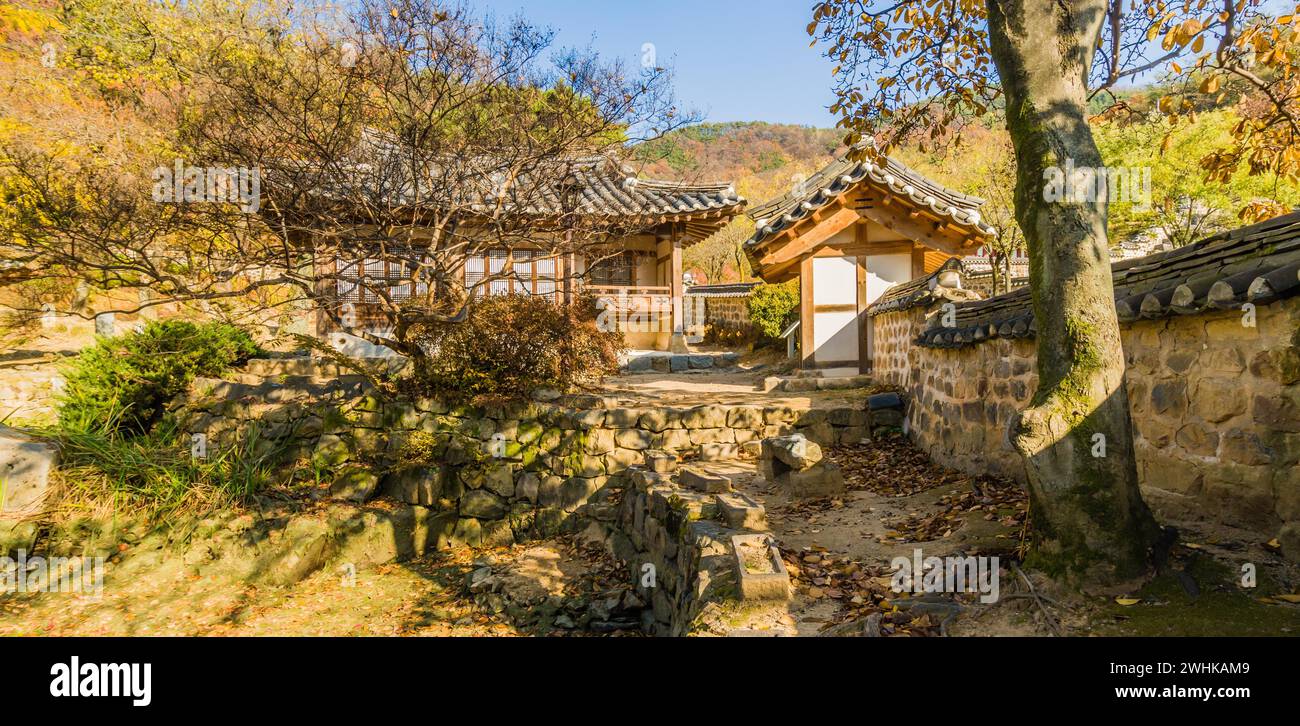 Stone wall running to a small oriental tiled roof gate next to a small ...