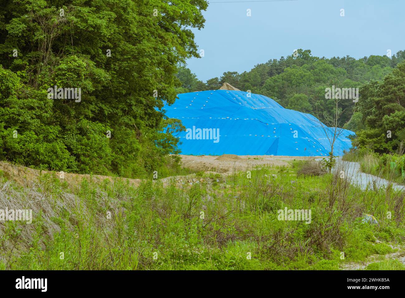 Large hill of dirt from construction site covered with blue tarp in ...