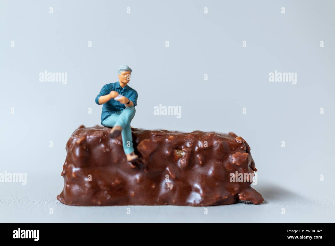 Business man sitting on chocolate bars with gray background. World ...