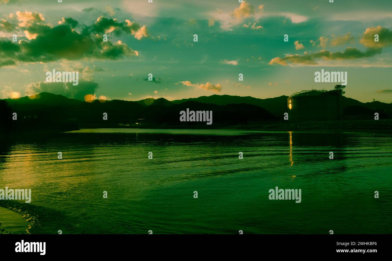 Dramatic blue cloudy sky over petroleum storage silo on bank of coastal ...