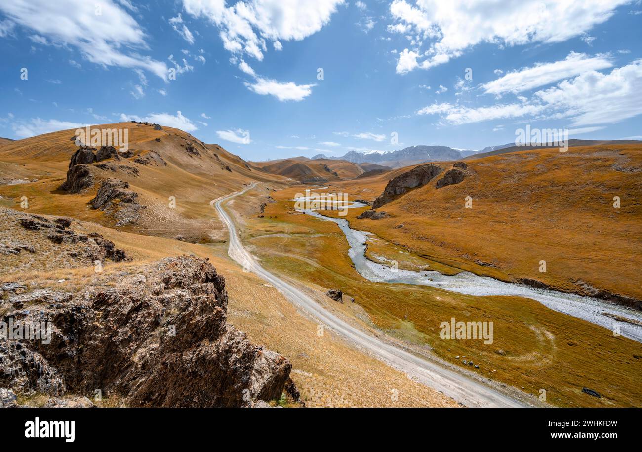 River Kol Suu winds through a mountain valley with hills of yellow ...