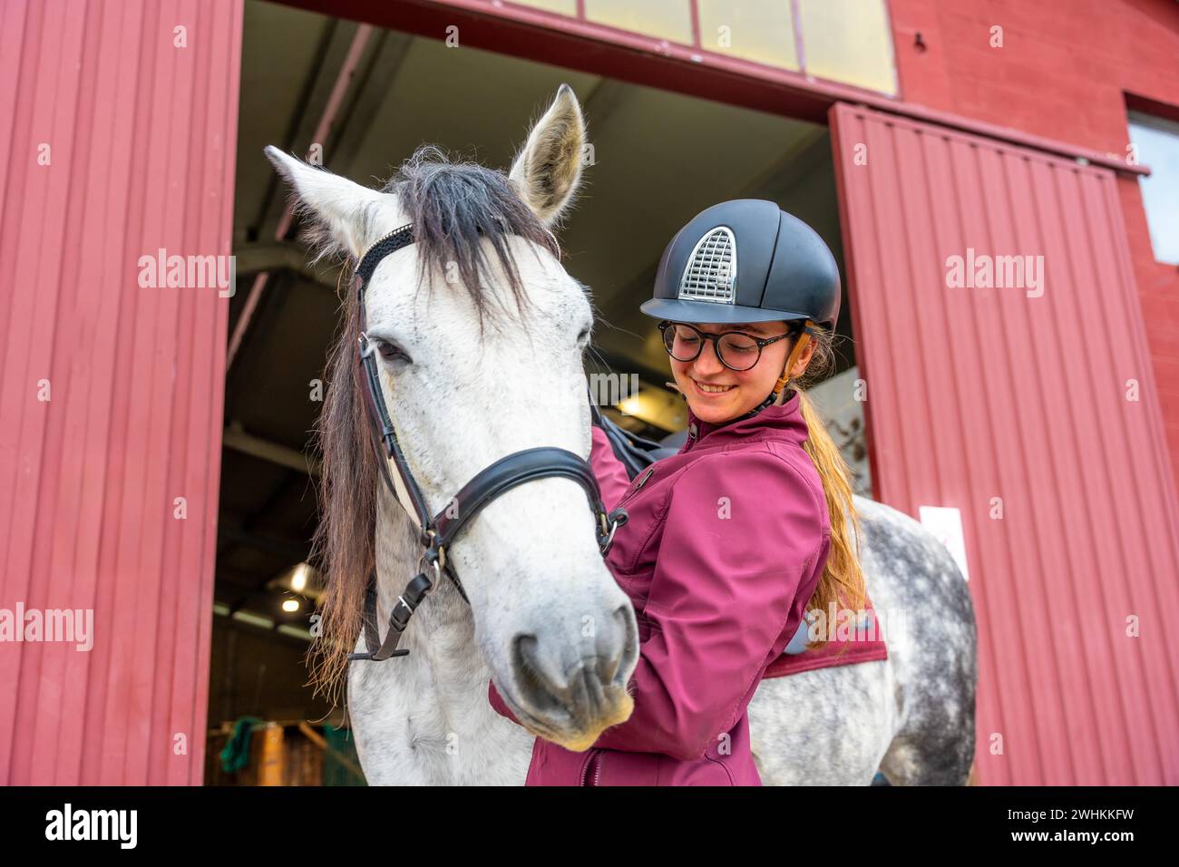 Low angle view photo of a female young jockey caressing her horse ...