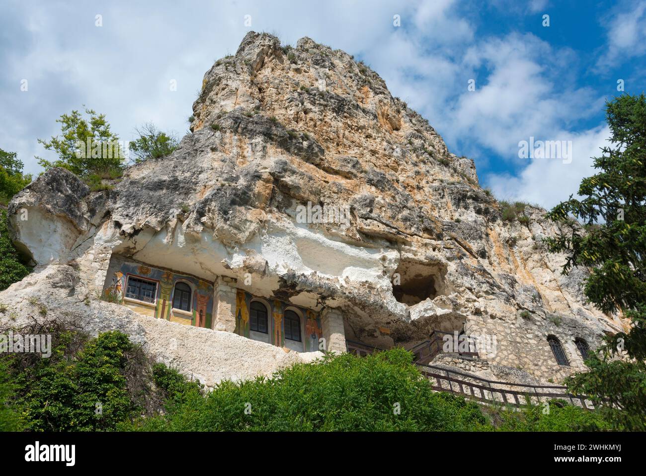 Historic cave church built into a steep rock under a clear blue sky ...