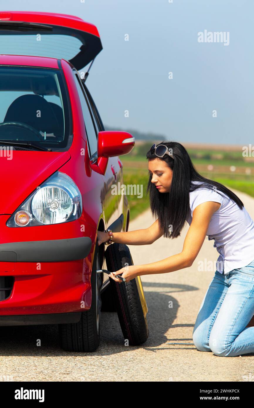 Young woman changes a tyre on her car, puncture Stock Photo - Alamy