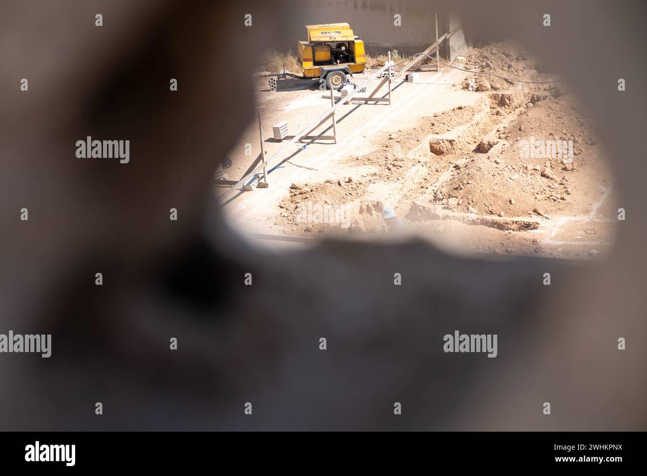 a photo through a hole for a workers are digging up the foundations for ...