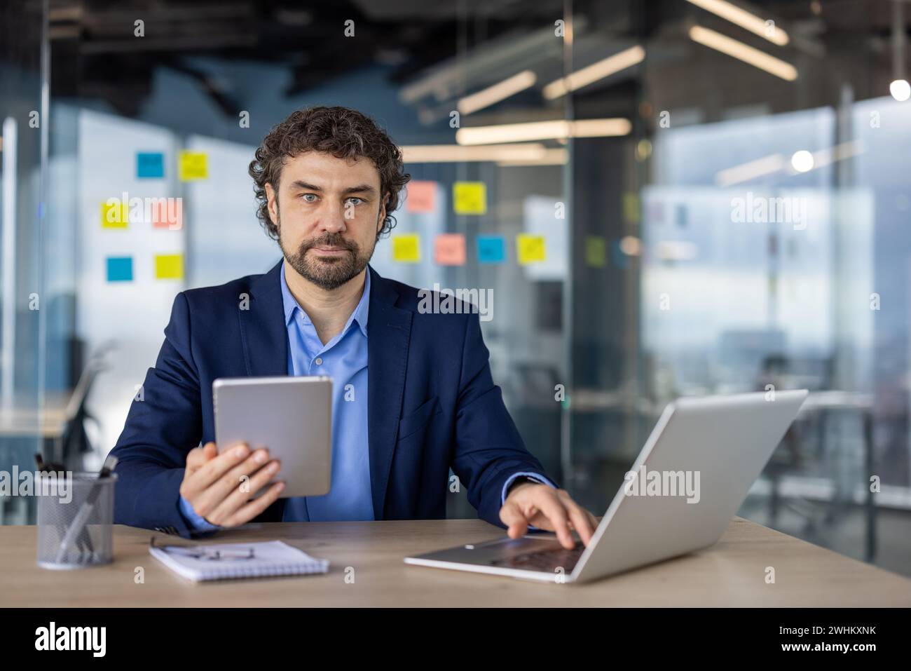 Portrait of serious confident businessman at workplace inside office ...