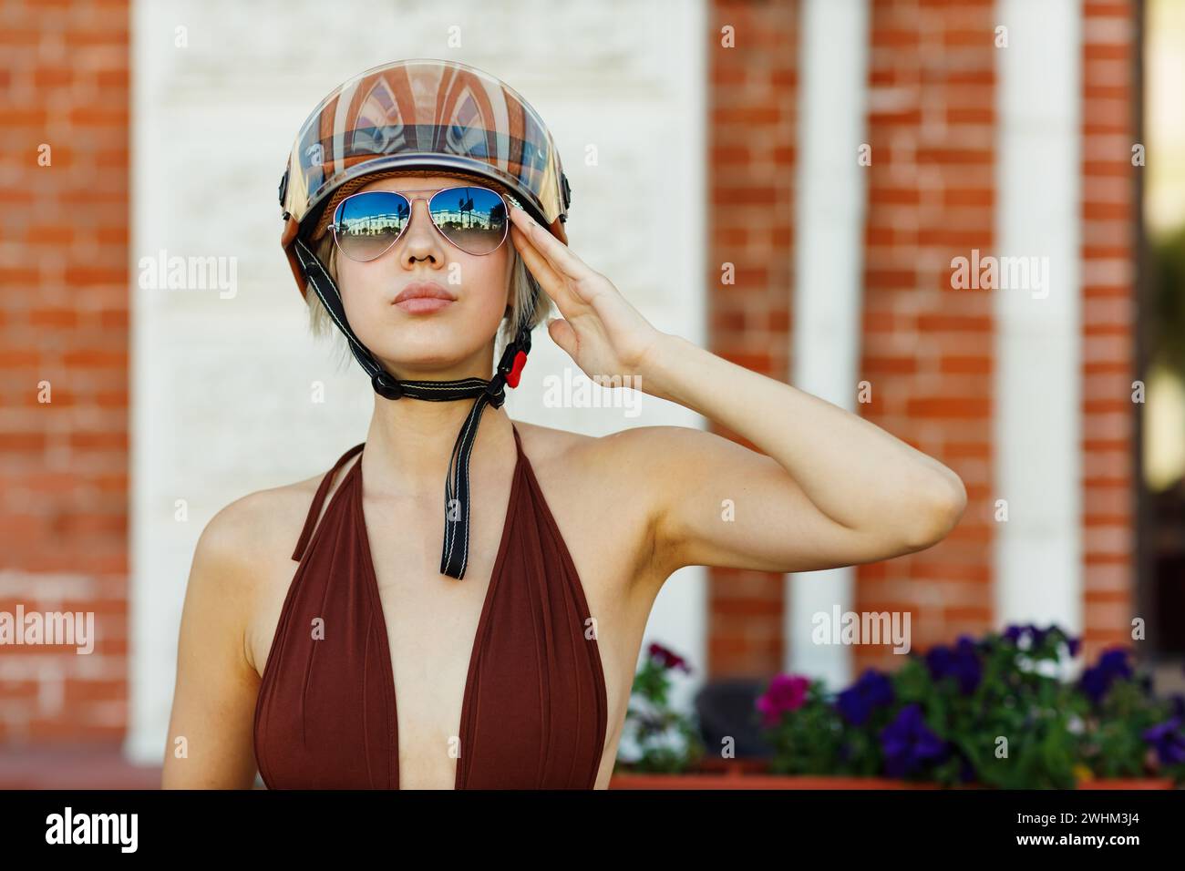 Young woman pilot in helmet and sunglasses salutes hold hand at head ...