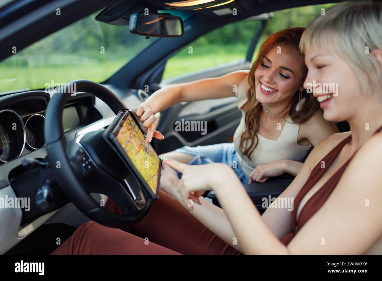 Happy young two women driver tourist travelers with digital tablet pad ...
