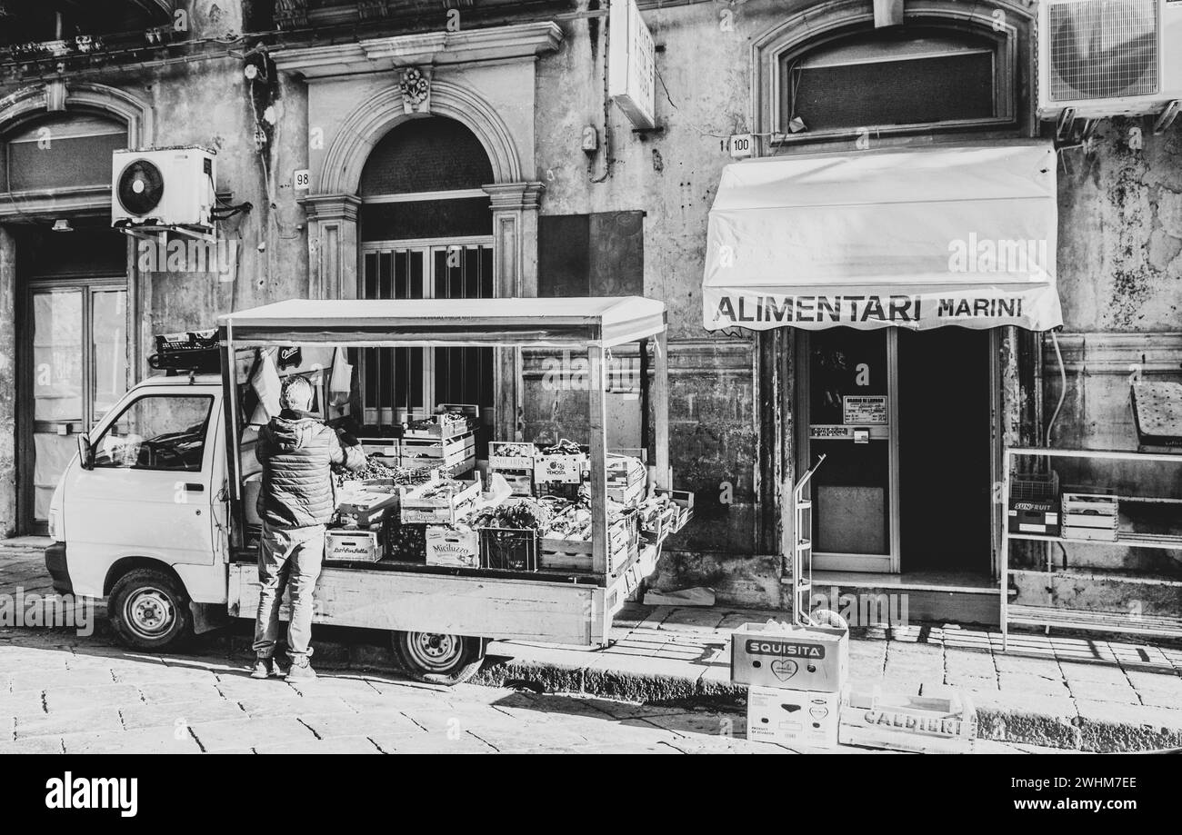 green grocer with his truck parked on the street, in front of the store ...