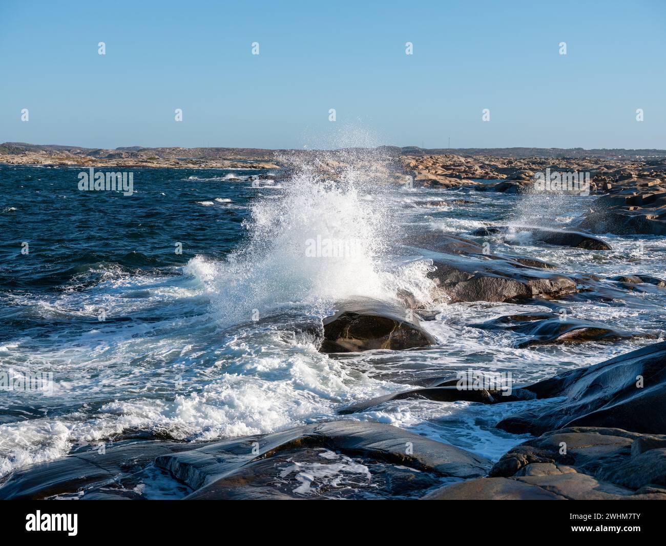 Ocean wave crashes into cliffs creating big splash with white foam ...