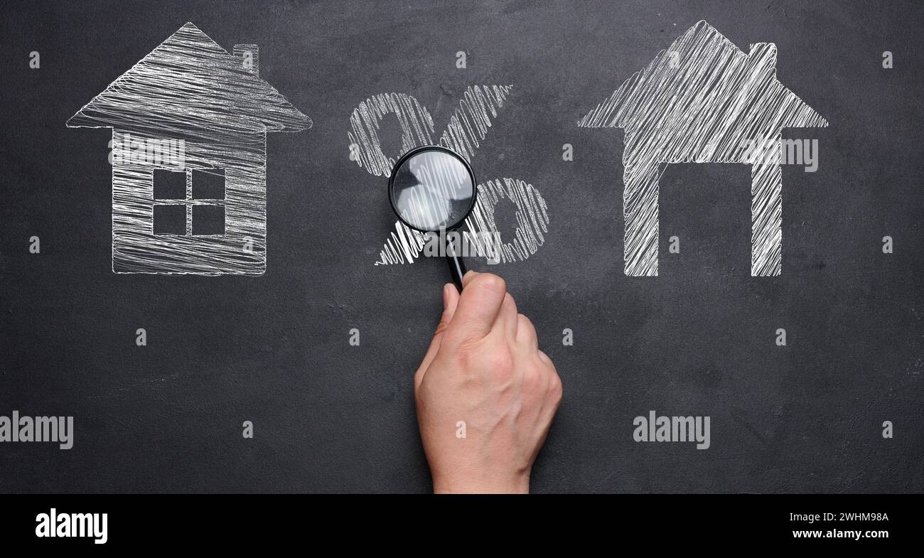 Chalk-drawn houses and a percentage sign on a blackboard, a female hand ...