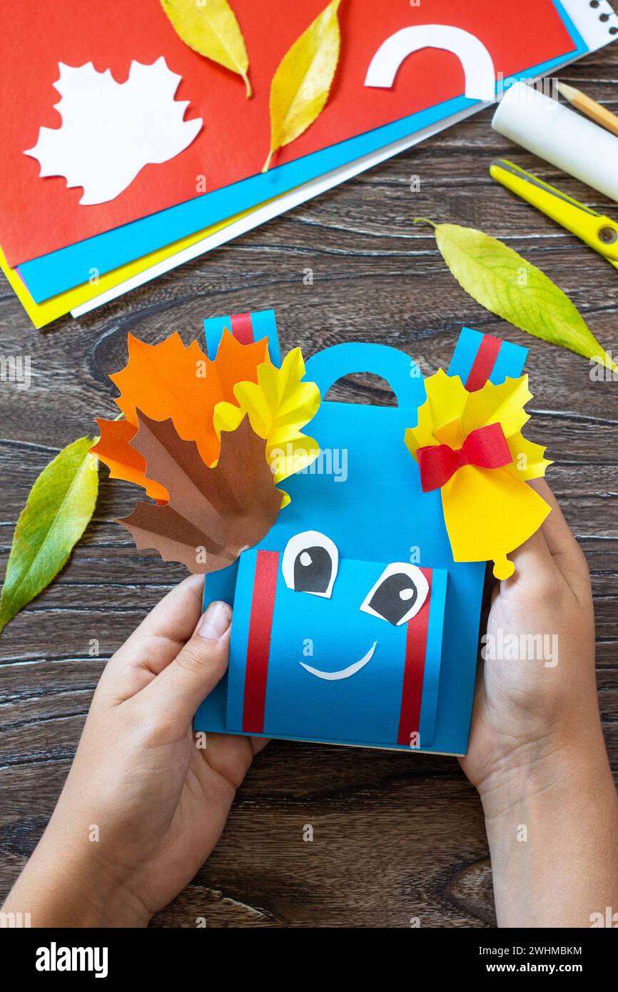 Greeting card paper backpack on a wooden table. Back to school concept. Handmade. Project of ...