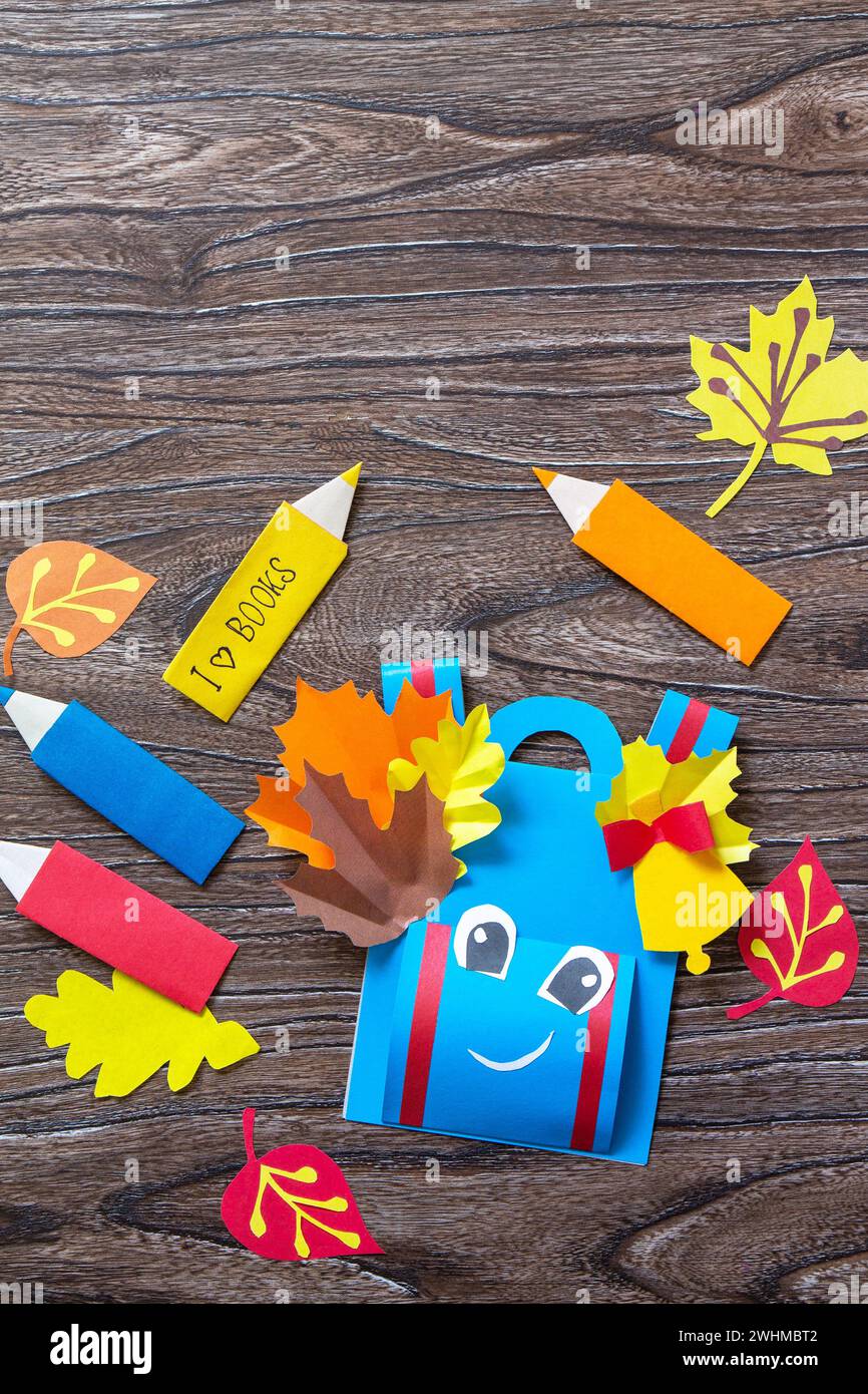 Greeting card paper backpack on a wooden table. Back to school concept ...