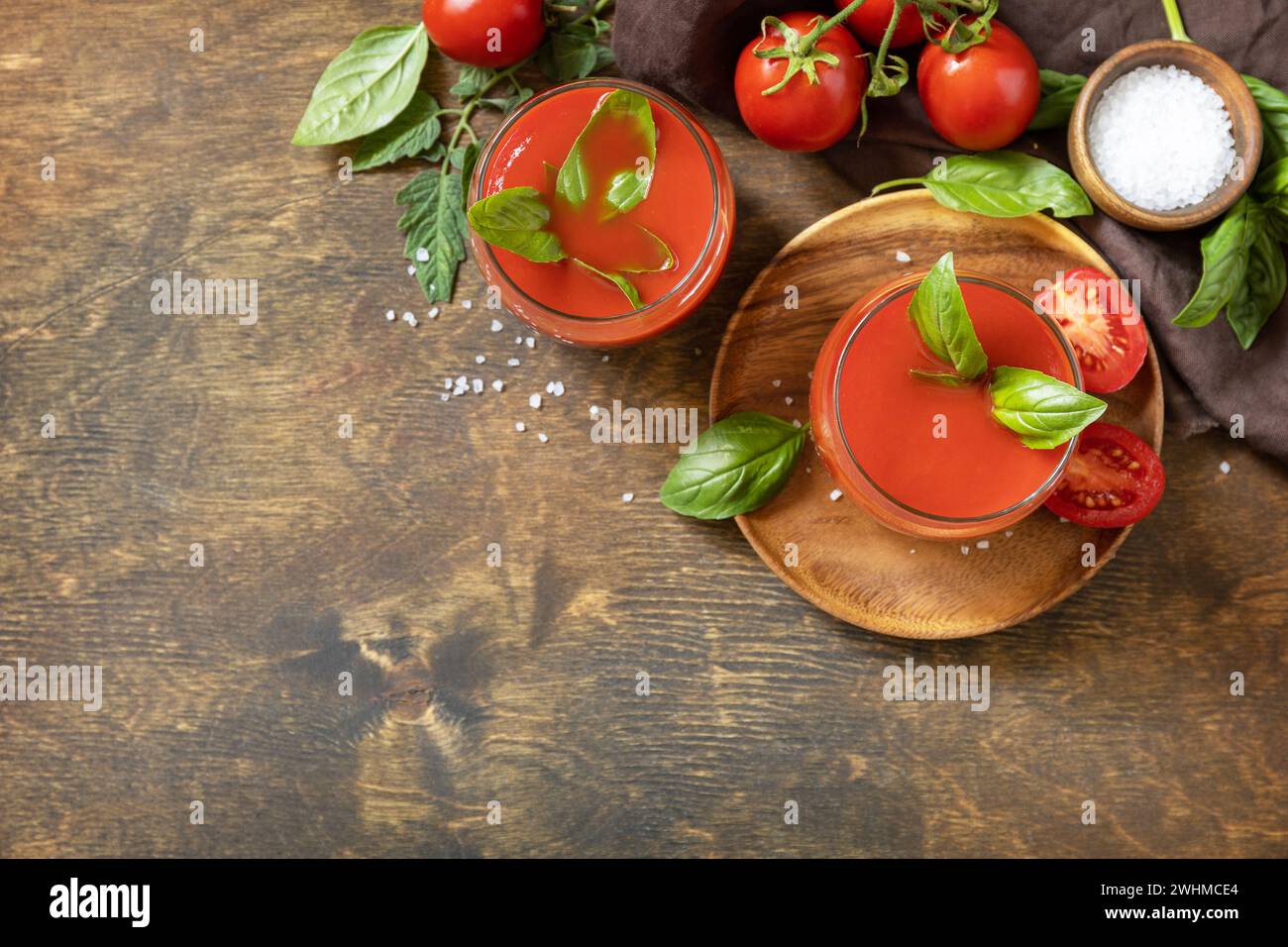 Glasses of fresh tomato juice with tomatoes, salt on wooden table ...