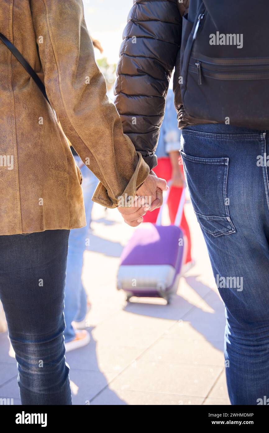 Unrecognizable adult tourist man and woman holding hands backwards ...