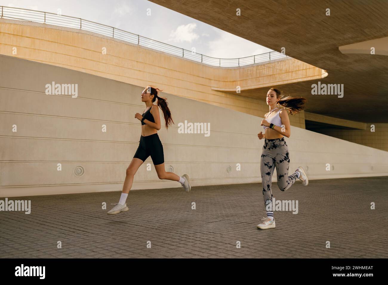 Two active women athlete running side by side along an outdoor track on ...