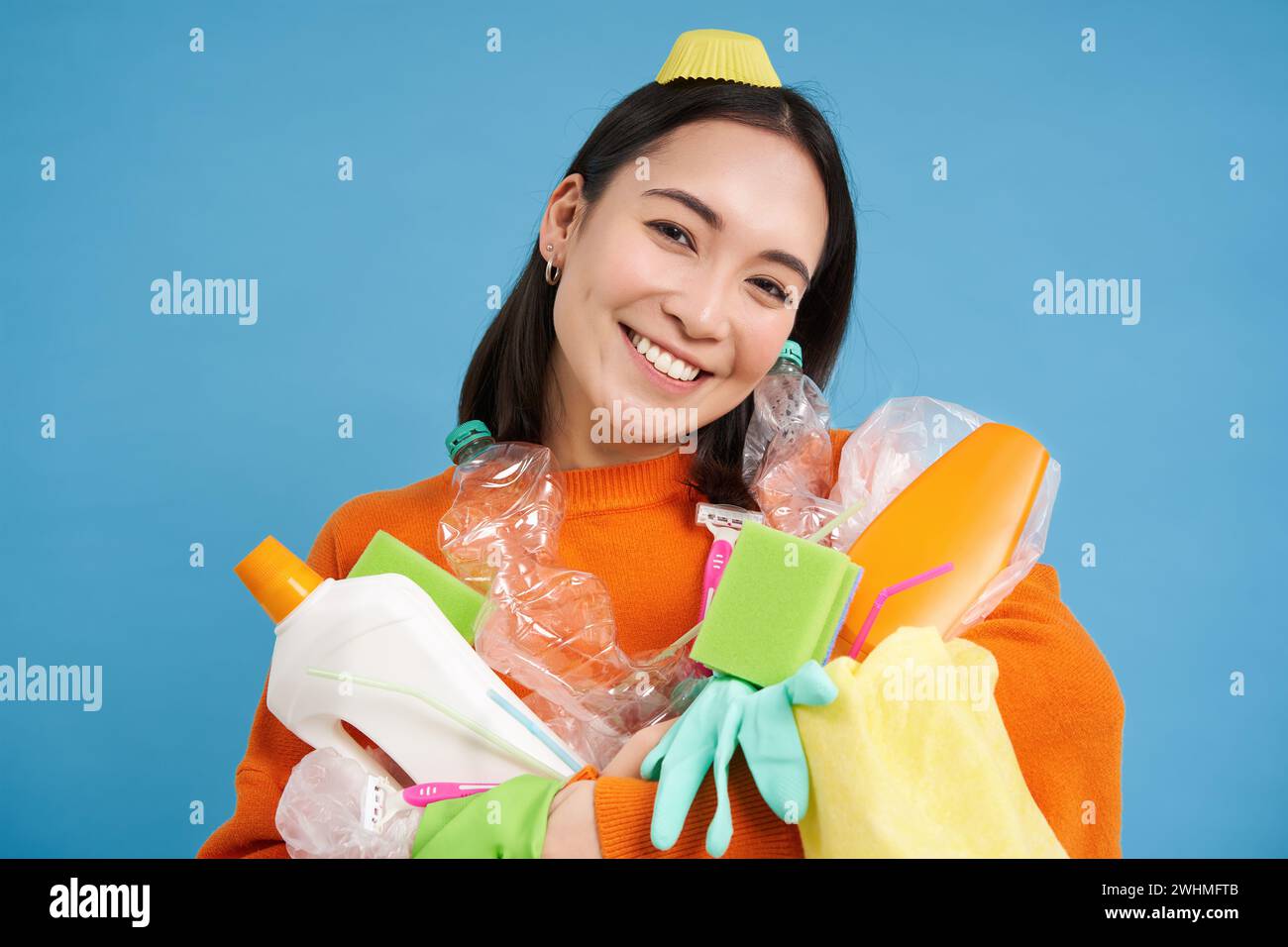 Portrait of smiling korean girl, holding sorted garbage for recycling ...