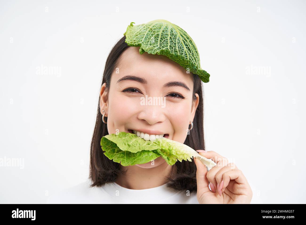Portrait of asian girl with leaf on head, eats cabbage and smiles ...