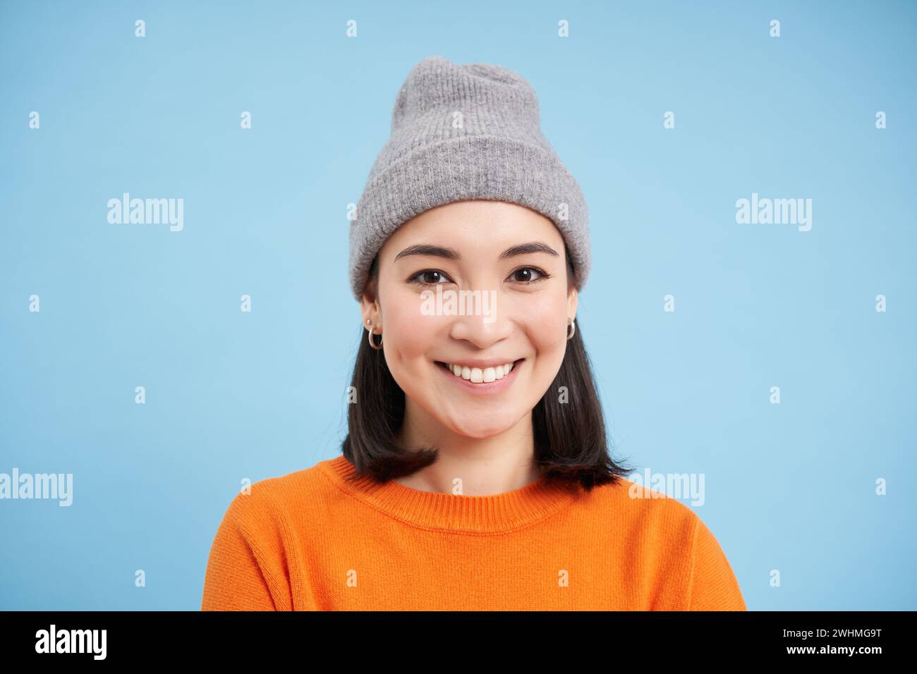 Close up portrait of smiling asian woman in warm hat, looking happy and ...