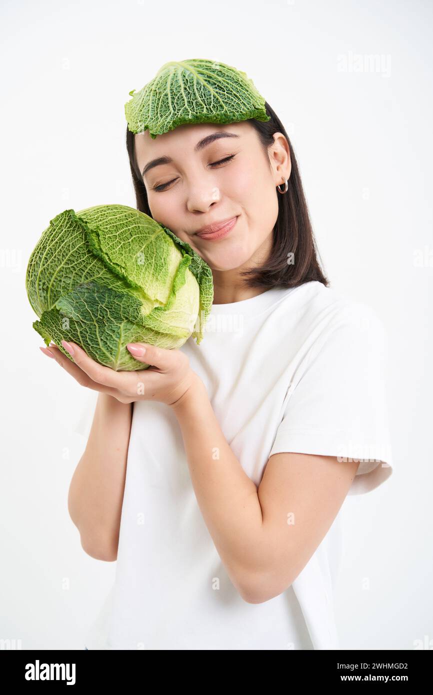Vertical portrait of smiling korean woman, hugging cabbage, loves ...