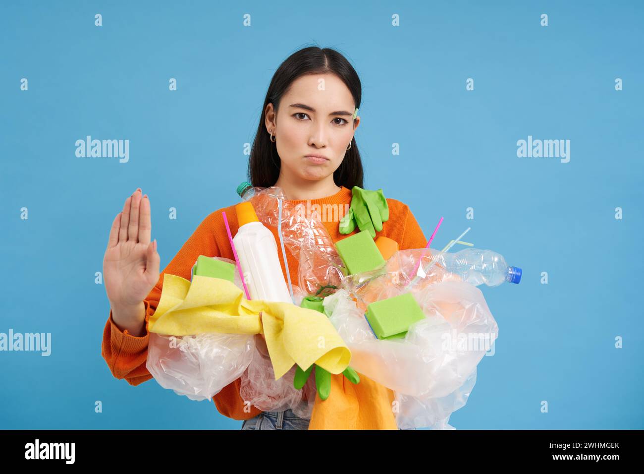 Serious eco activist shows stop sign and plastic waste, urges to stop ...