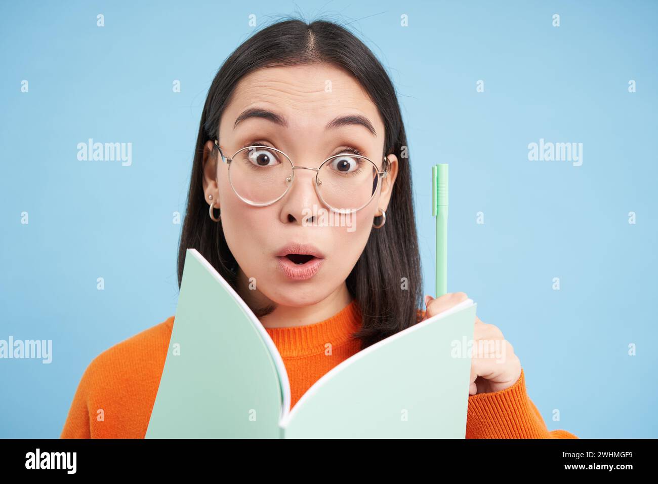 Amazed Young Asian Woman In Glasses Has An Idea Writes Down With Pen