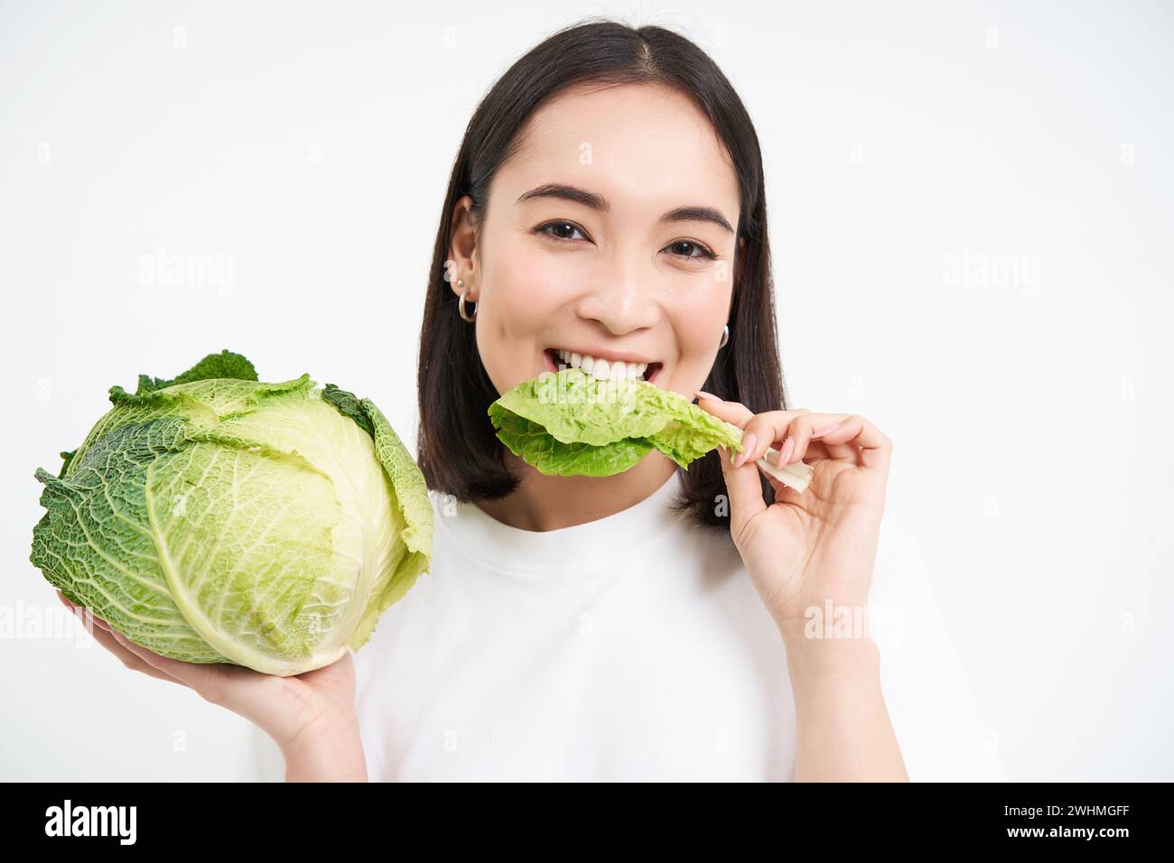 Close up portrait of asian woman, biting lettuce, eating green cabbage ...