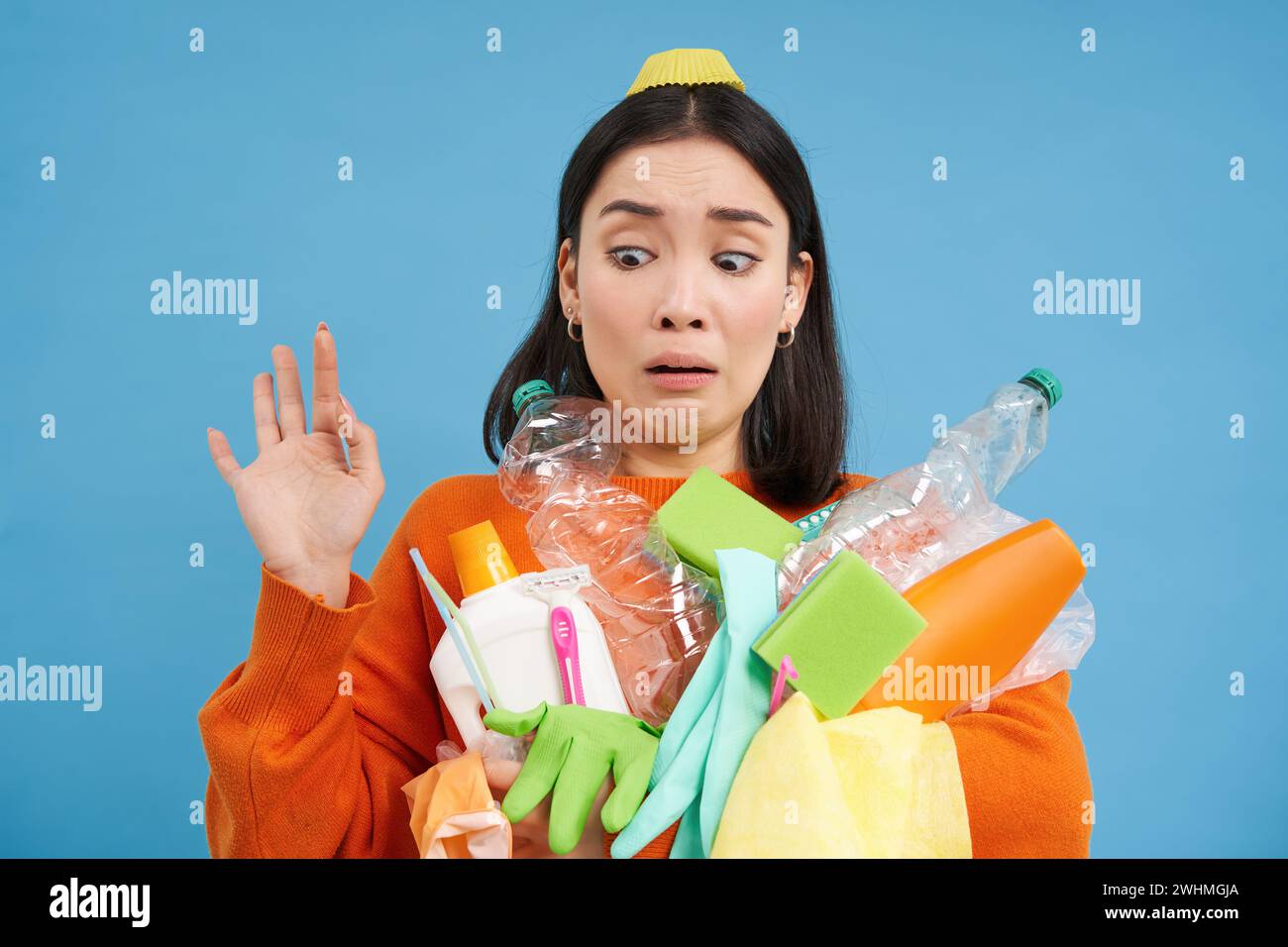 Disgusted asian woman, holding empty bottles, garbage for recycling ...