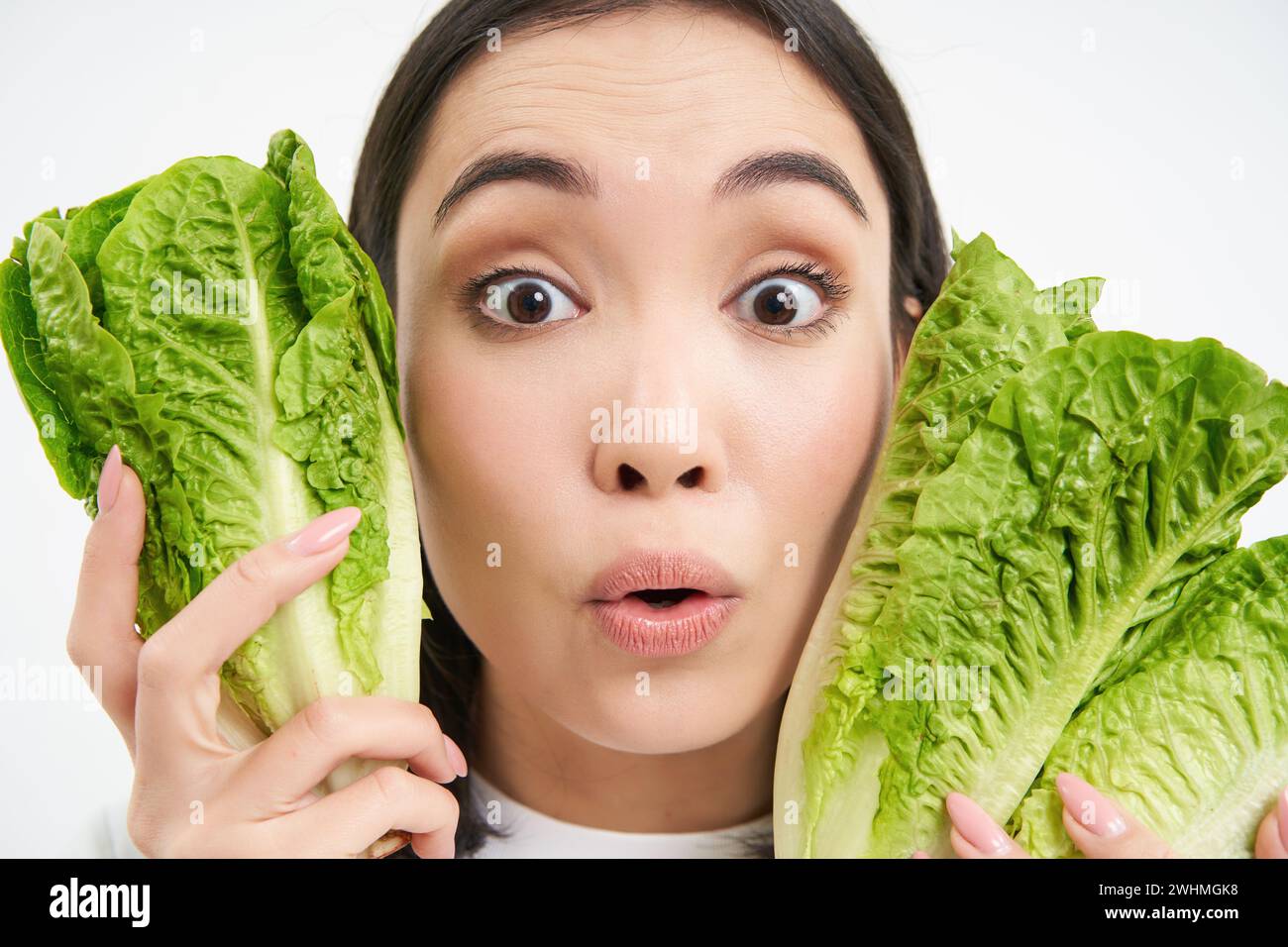 Portrait of cute young woman shows her face with cabbage, likes ...