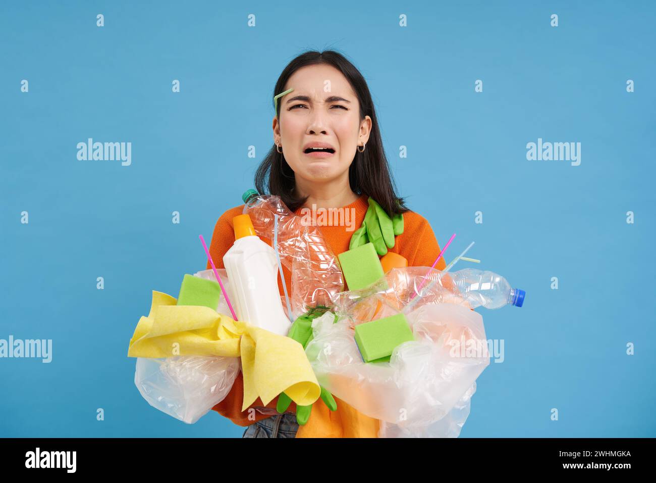 Crying asian female holding plastic waste, garbage in hands and looking ...