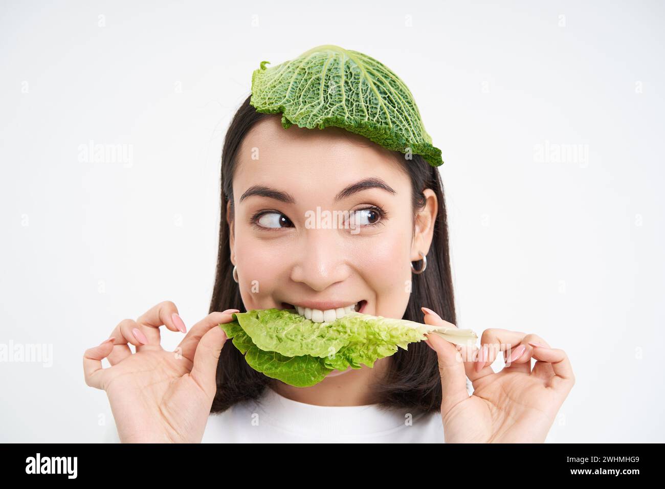 Portrait of asian girl with leaf on head, eats cabbage and smiles ...