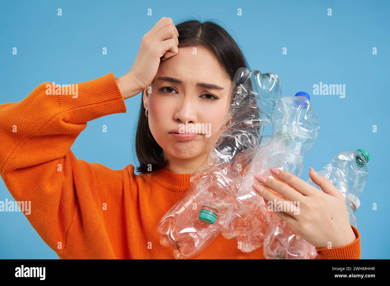 Troubled asian woman holding plastic bottles, trying find recycling ...