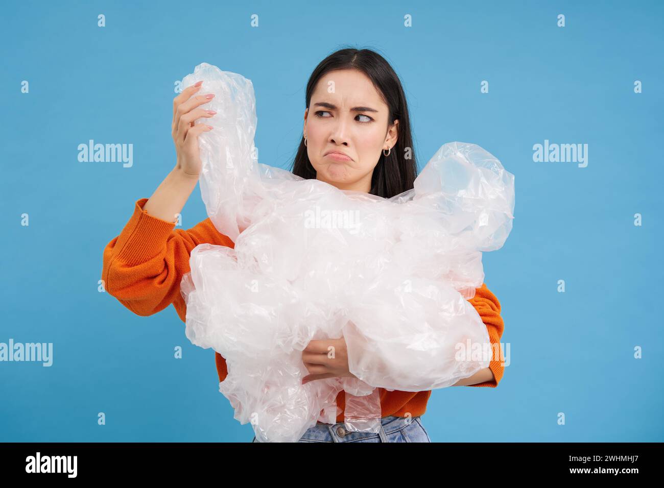 Young asian woman with plastic waste, looking bothered by recycling ...