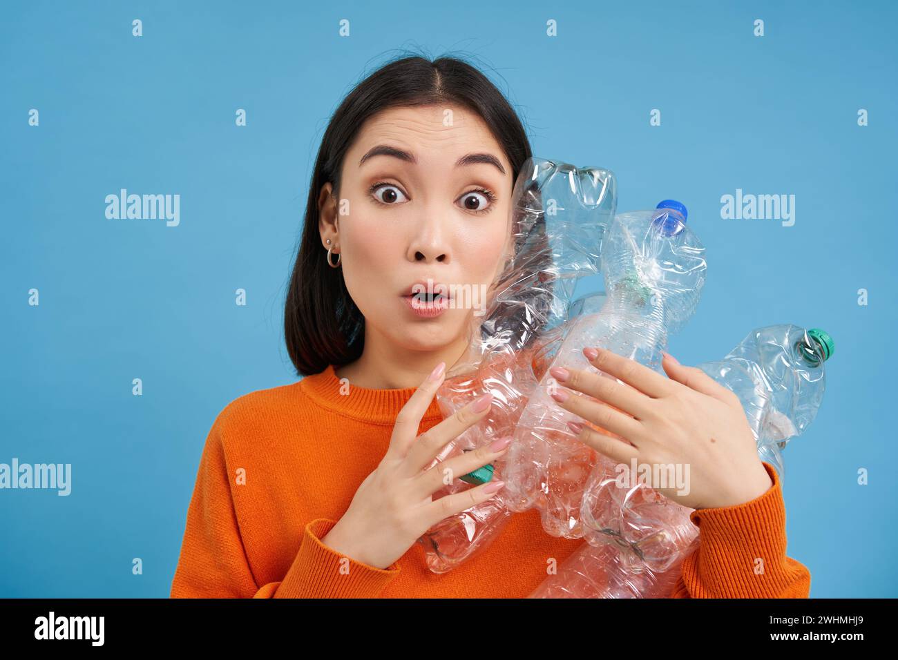 Portrait of cute korean woman, holding two plastic bottles with excited ...