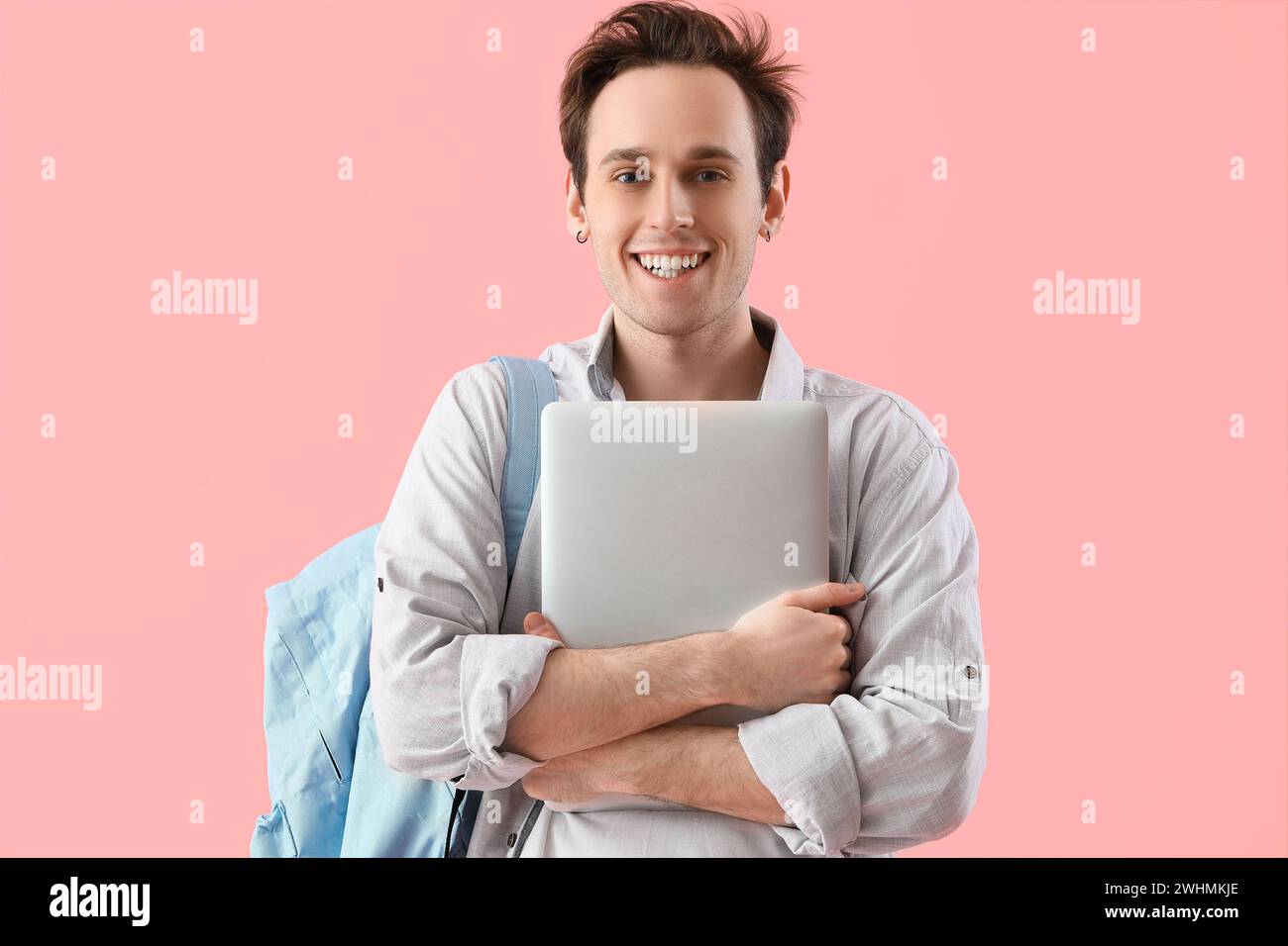Male student with laptop on pink background Stock Photo - Alamy
