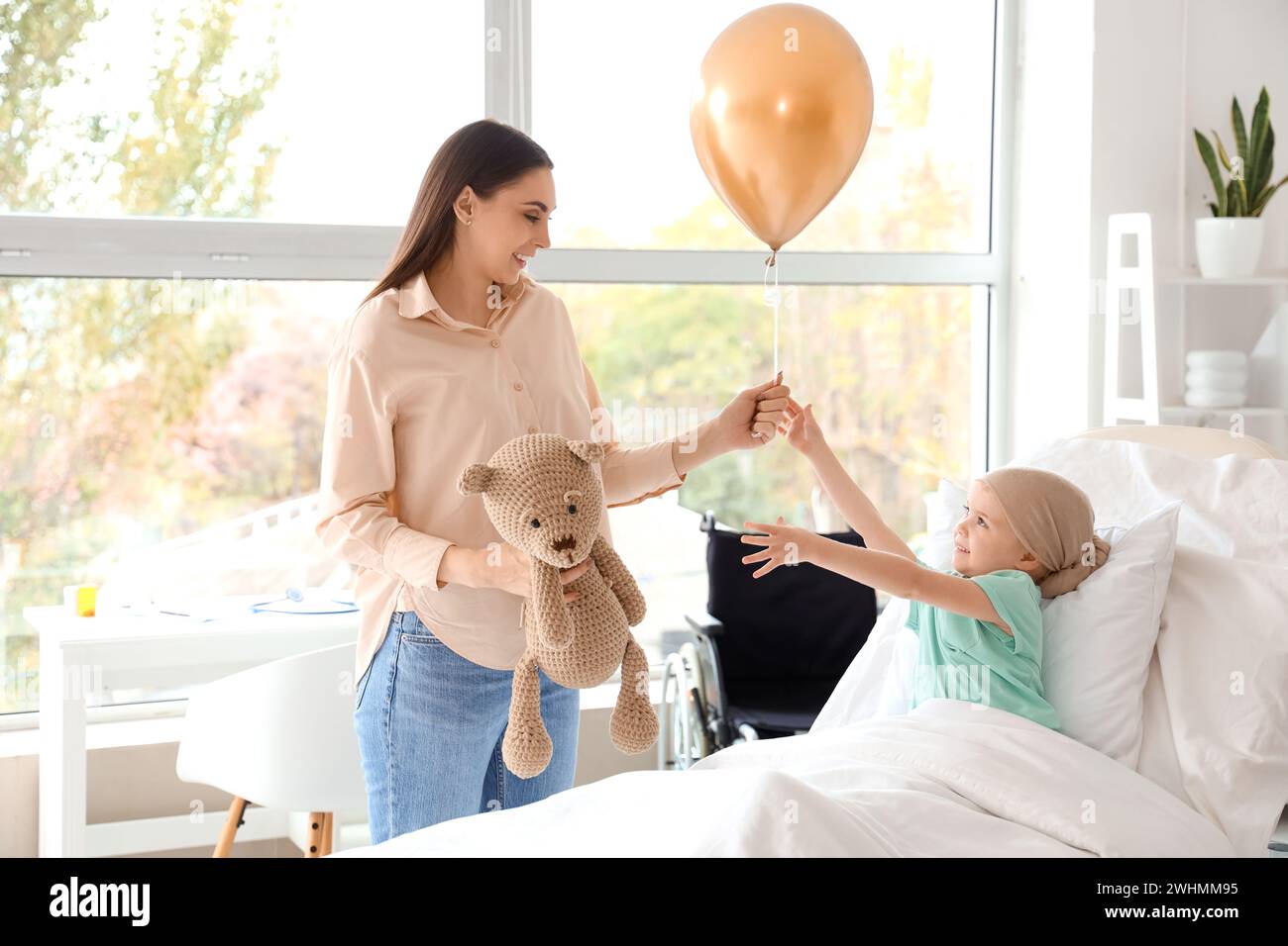 Little girl after chemotherapy receiving golden balloon and toy bear ...