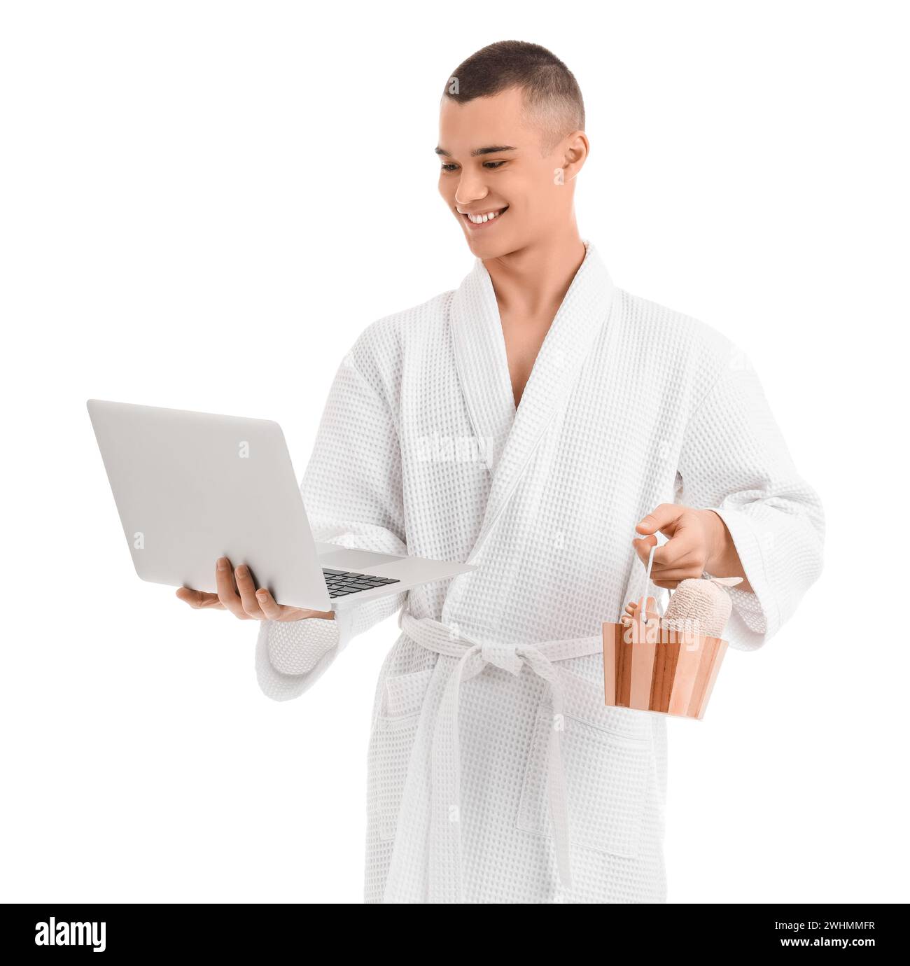 Teenage boy in bathrobe with shower supplies and laptop on white ...