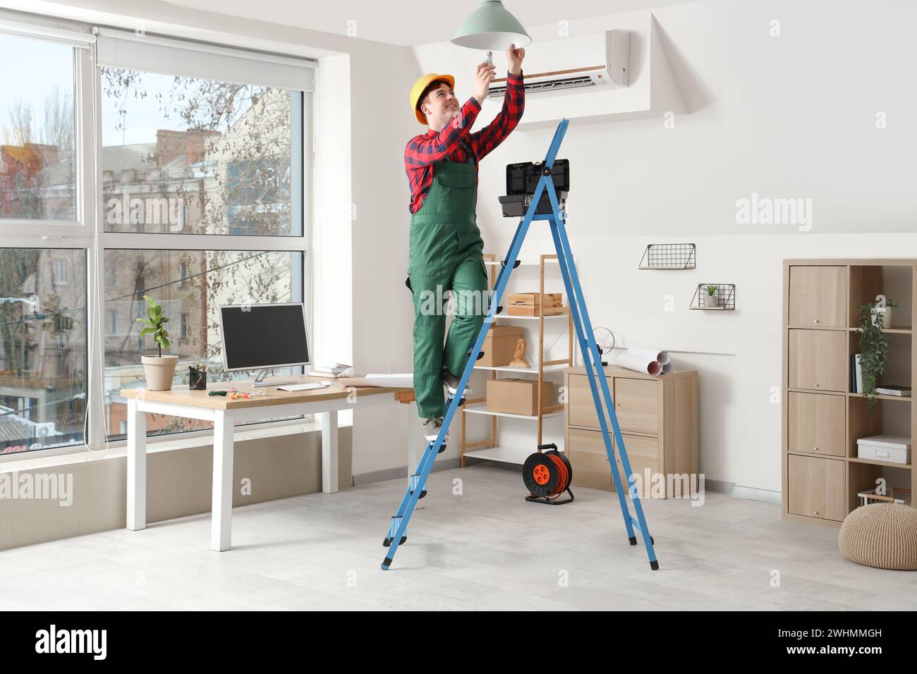 Male electrician on stepladder changing light bulb in room Stock Photo ...