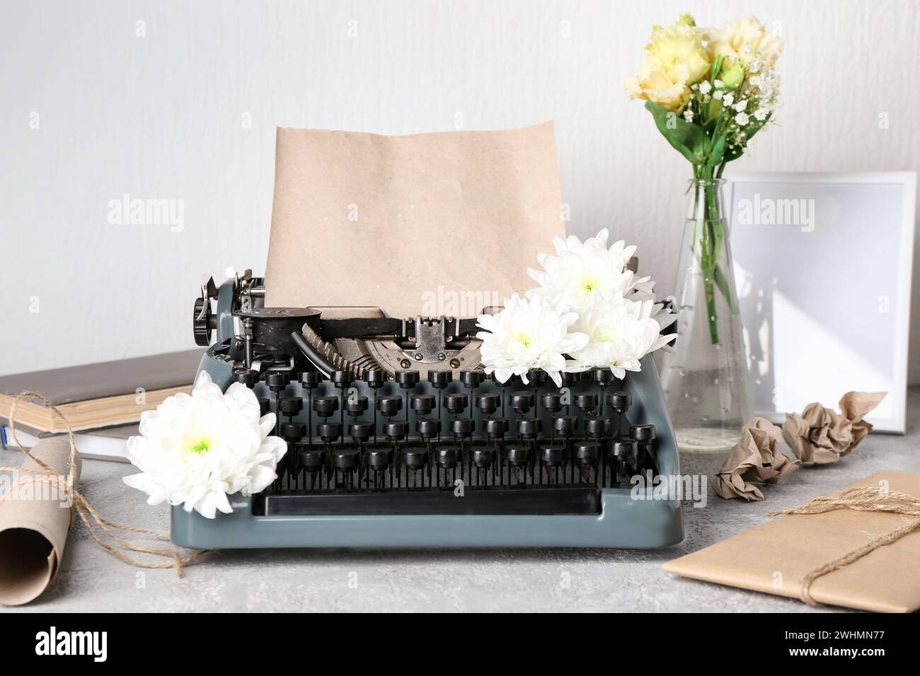 Vintage typewriter with craft paper, photo frame and flowers on grey ...