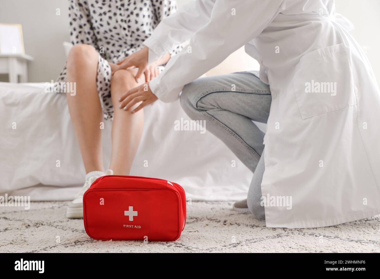 Doctor examining traumatized woman's knee in bedroom Stock Photo - Alamy
