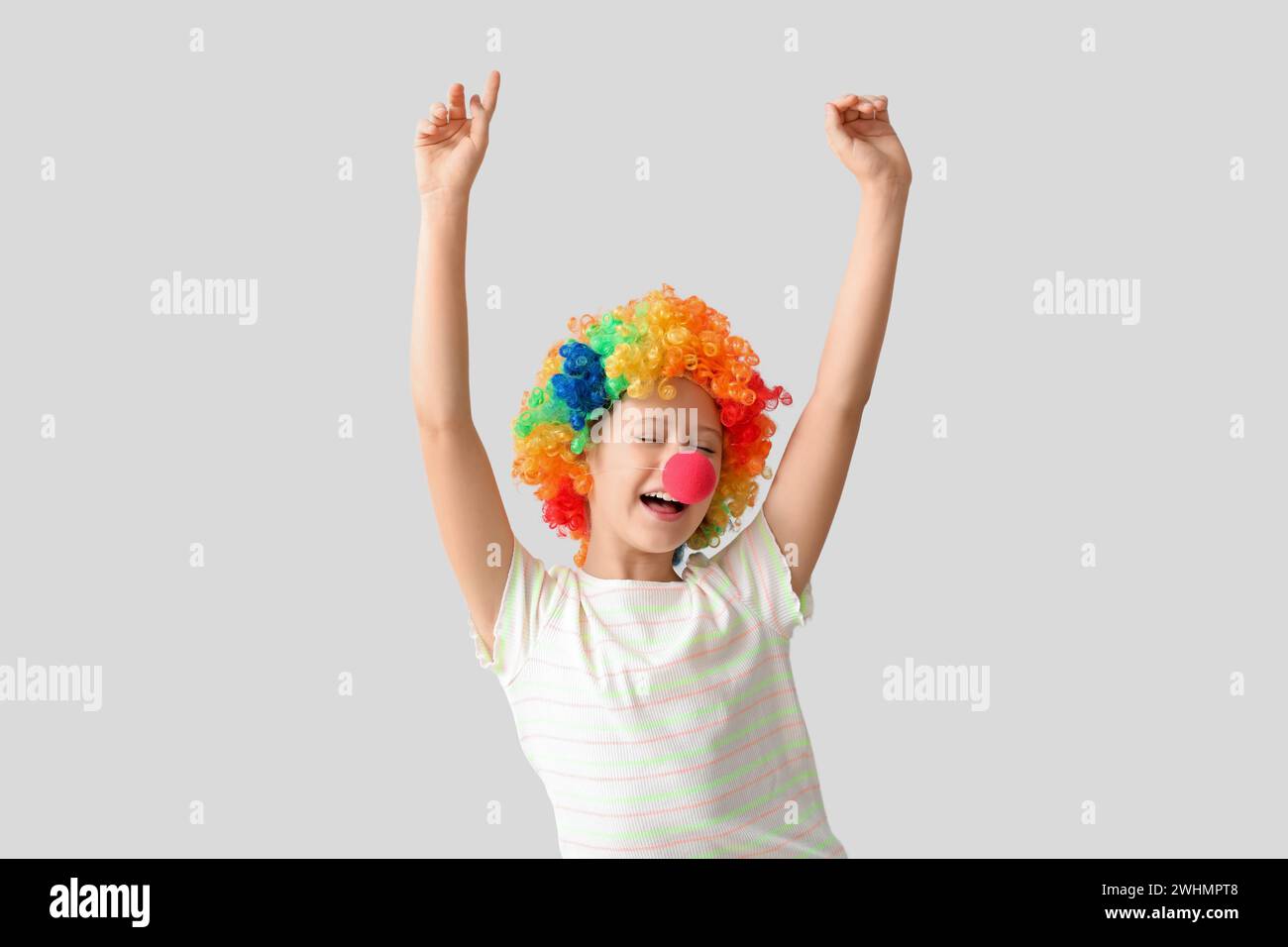 Funny girl in clown costume on white background. April Fool's Day ...