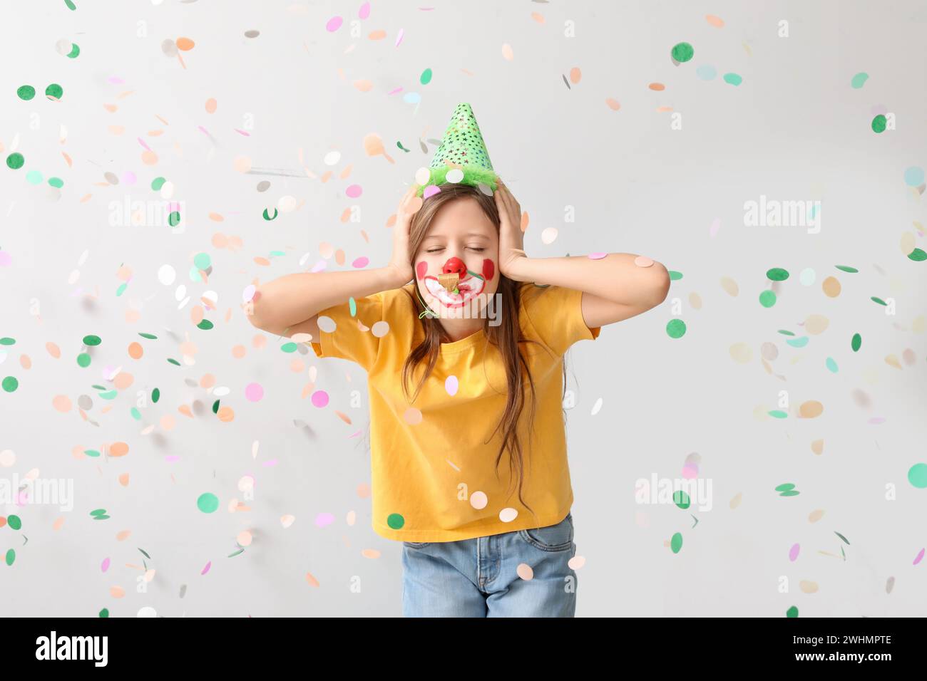 Funny girl with clown makeup, party hat, whistle and confetti covering ...