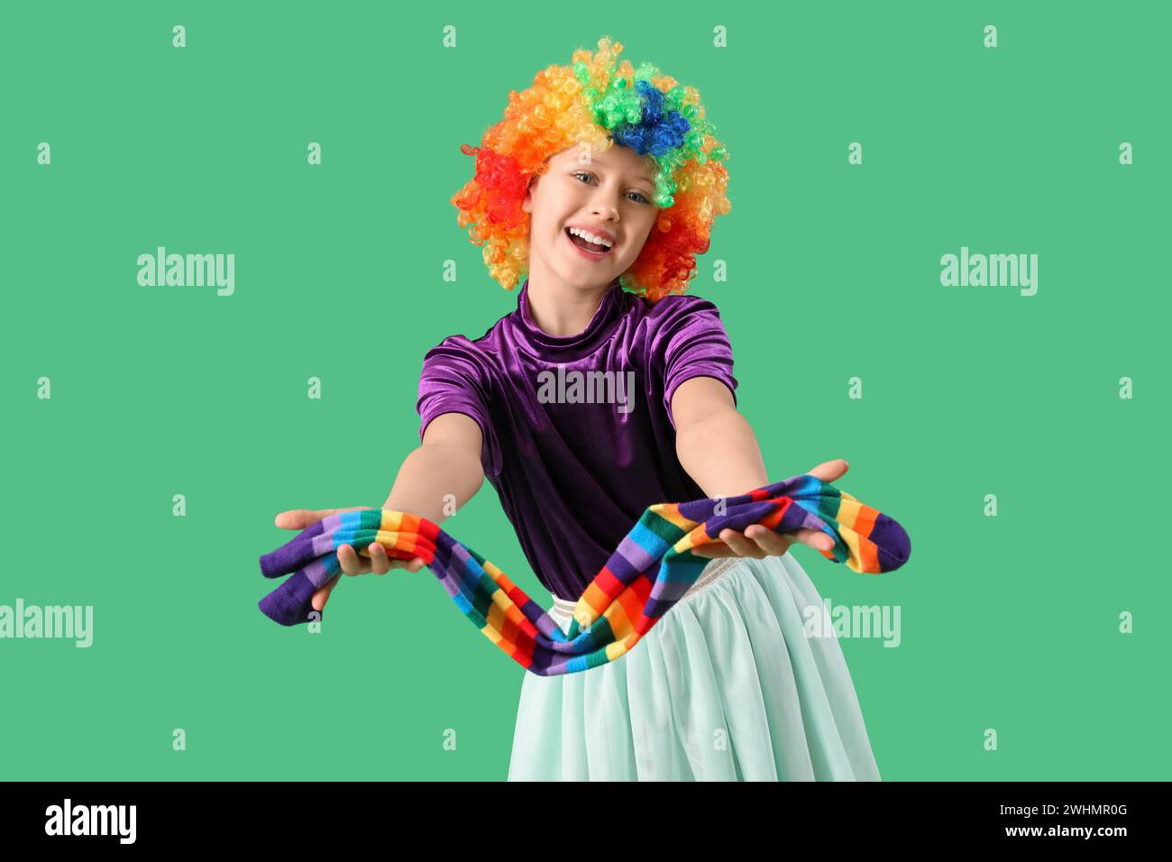 Funny girl in clown costume with colorful tights on green background ...