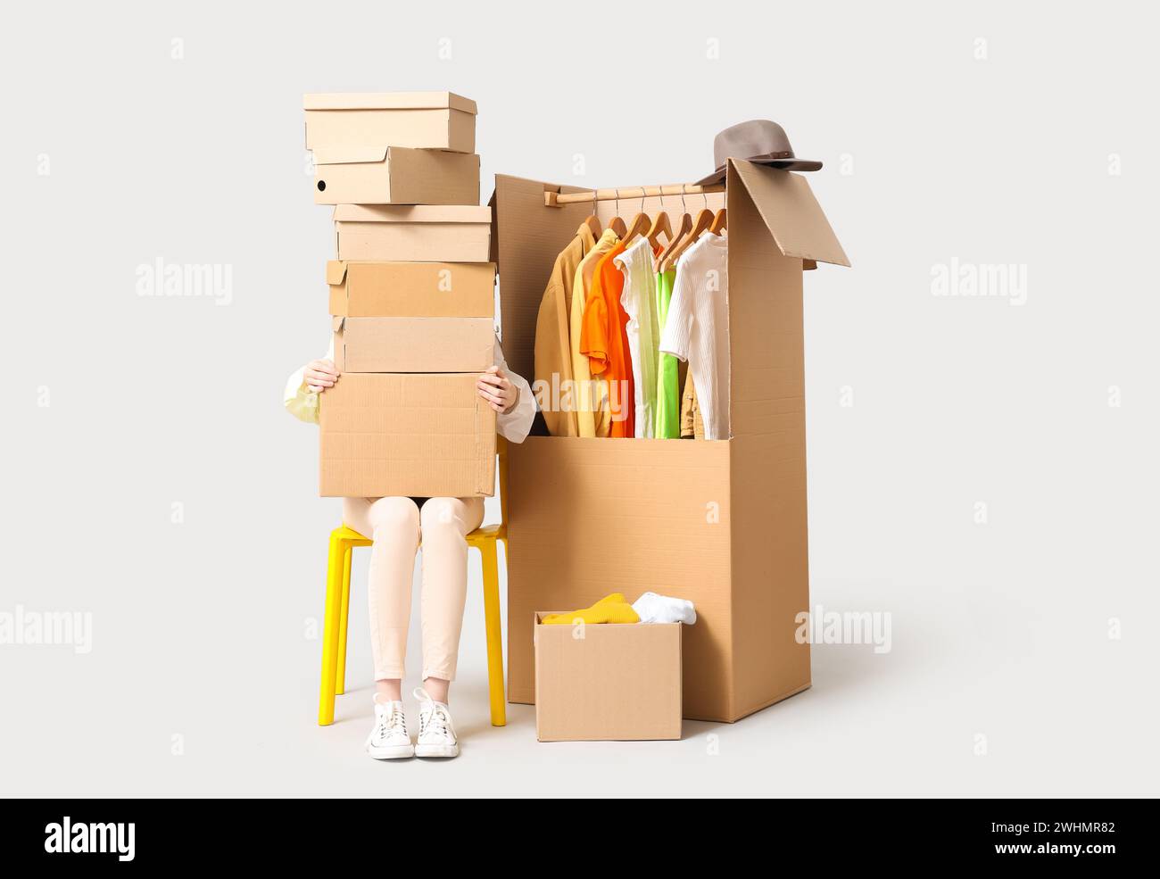 Beautiful young woman and wardrobe boxes with clothes on grey ...