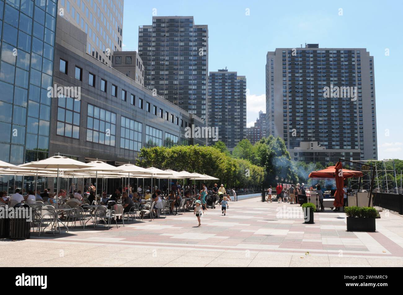 Public park with coffee shop and skyscrapers. People resting at ...